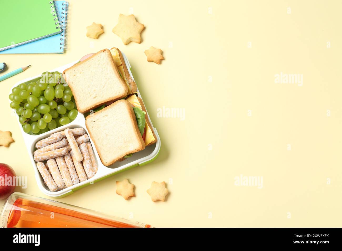 Lunch box with snacks, bottle and stationery on yellow table, flat lay ...