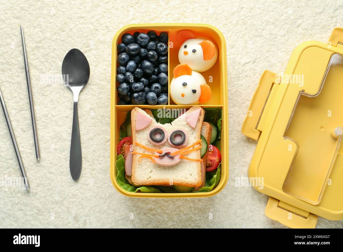 Lunch box with snacks, spoon and chopsticks on beige textured table ...