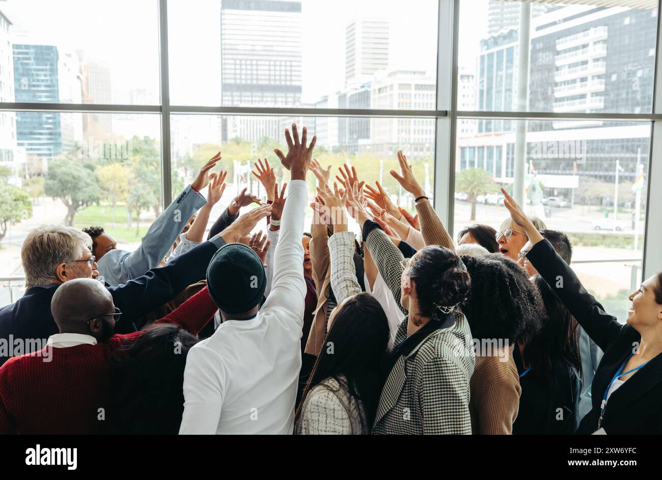 Diverse group of professionals raising their hands together, celebrating success and ...