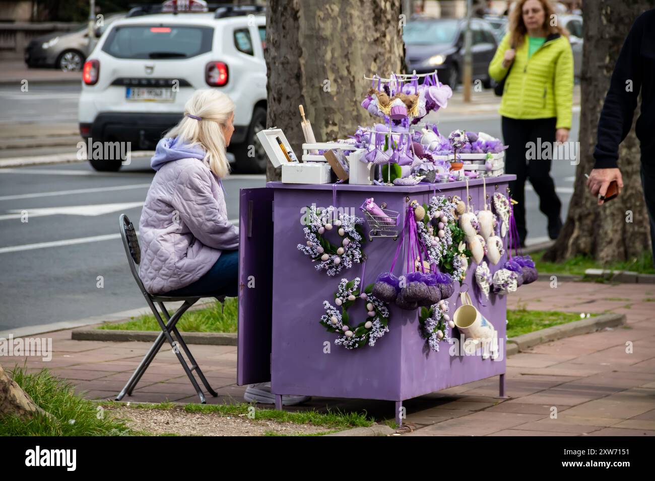 A senior lady sells lavender at a small street stand, both the stand ...