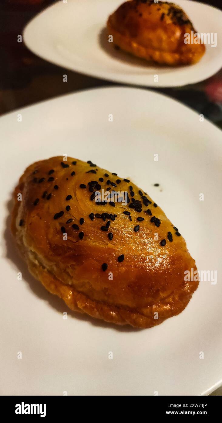Delicious flaky pastry samsa topped with black seeds on a clean plate ...
