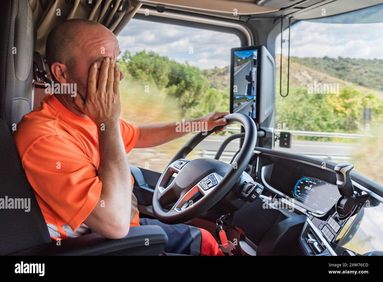 Truck driver driving the truck and rubbing his face with his hand in a ...