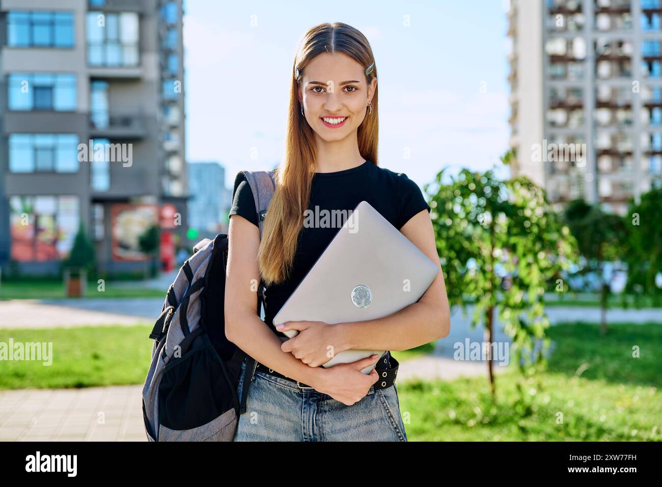 Portrait young female college student holding laptop computer outdoor ...