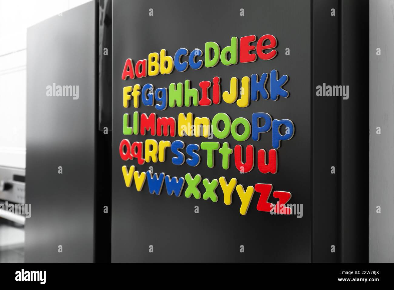 Alphabetical order. Many bright magnetic letters on fridge indoors ...