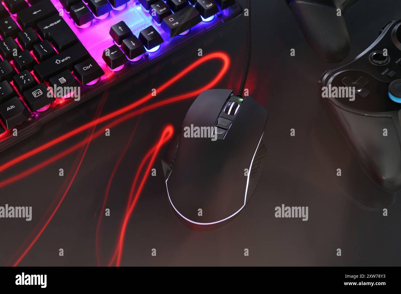 Computer mouse, RGB keyboard and game controllers in neon lights on ...