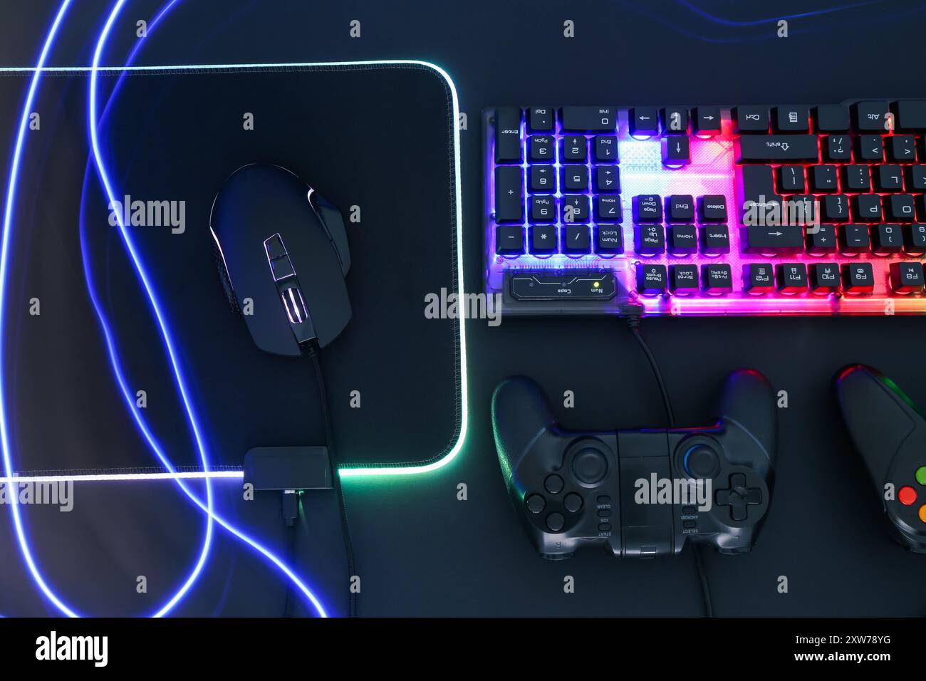 Computer mouse, RGB keyboard and game controllers in neon lights on ...