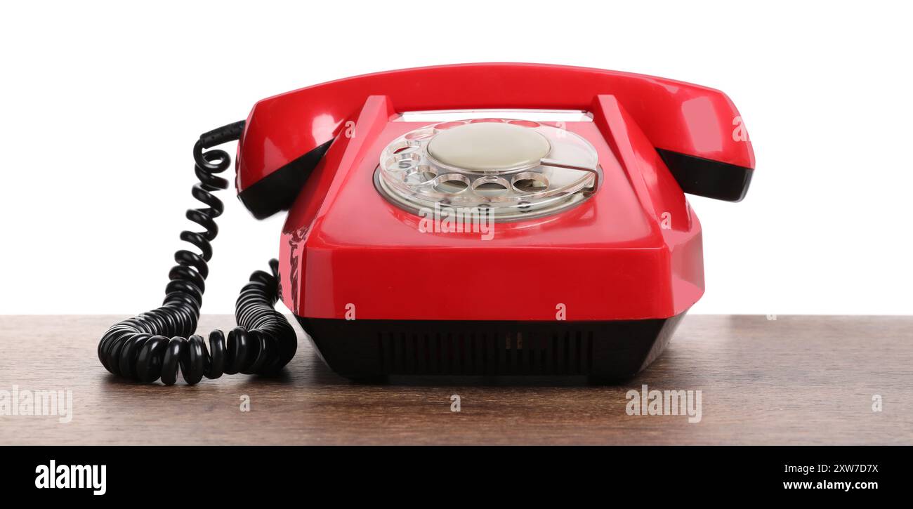 One red telephone with handset on wooden table against white background ...