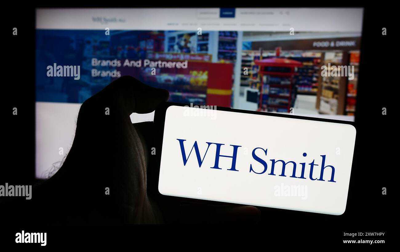Person holding smartphone with logo of British retail company WH Smith ...