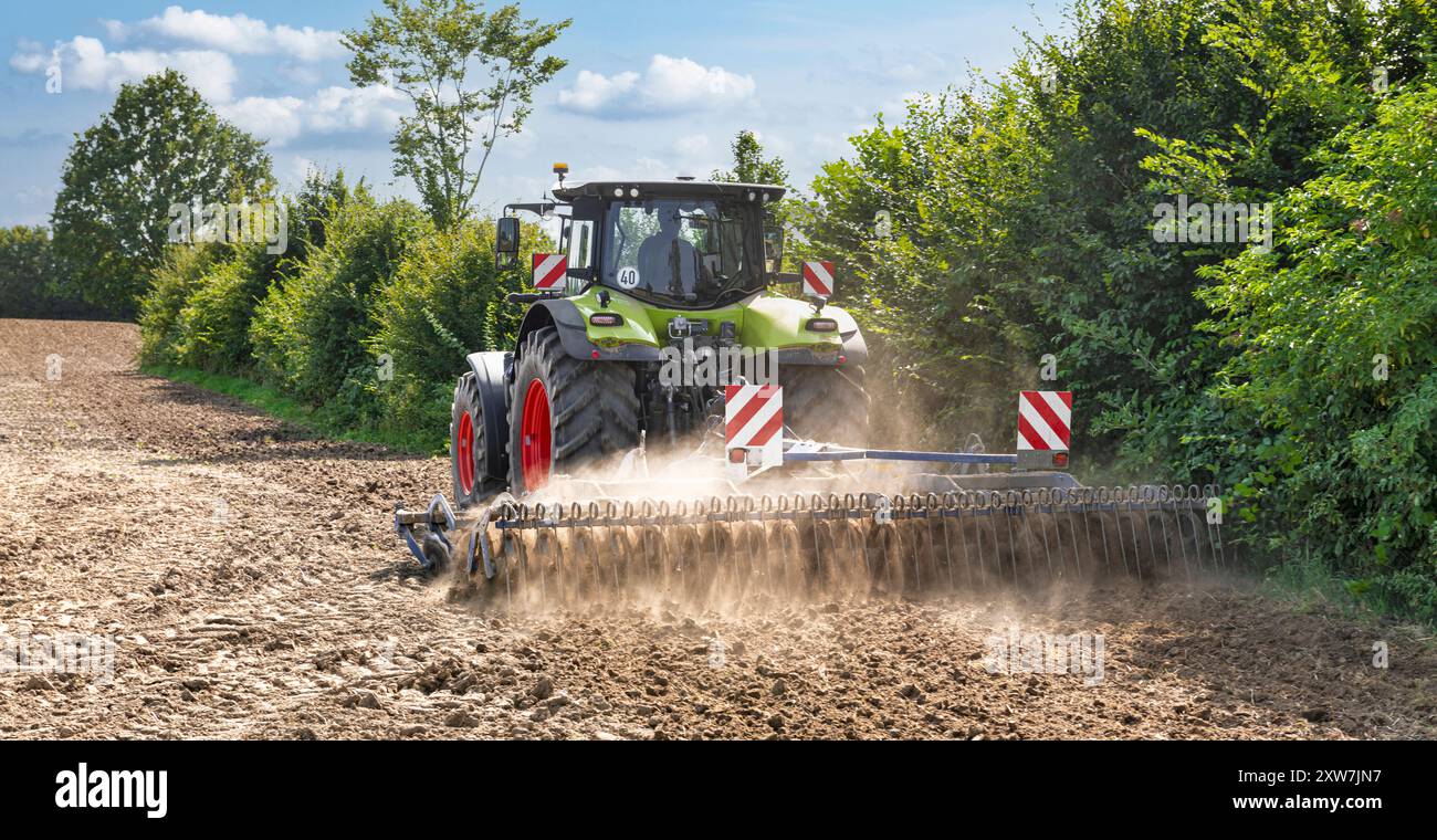 Tractor with cultivator working at the edge of the field after the ...