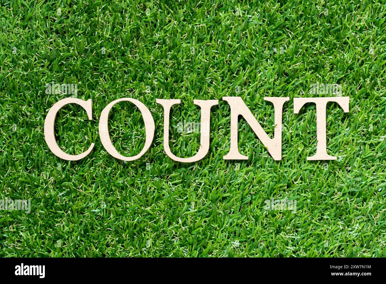 Wood alphabet letter in word count on artificial green grass background ...