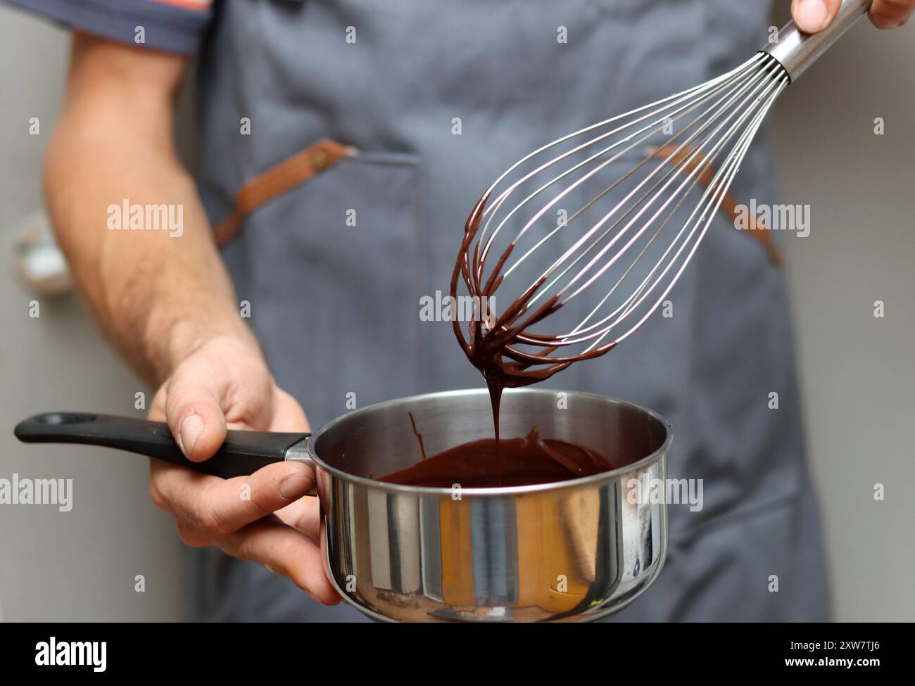 Chef making chocolate cake, closeup of hands holding a pot. Melted ...