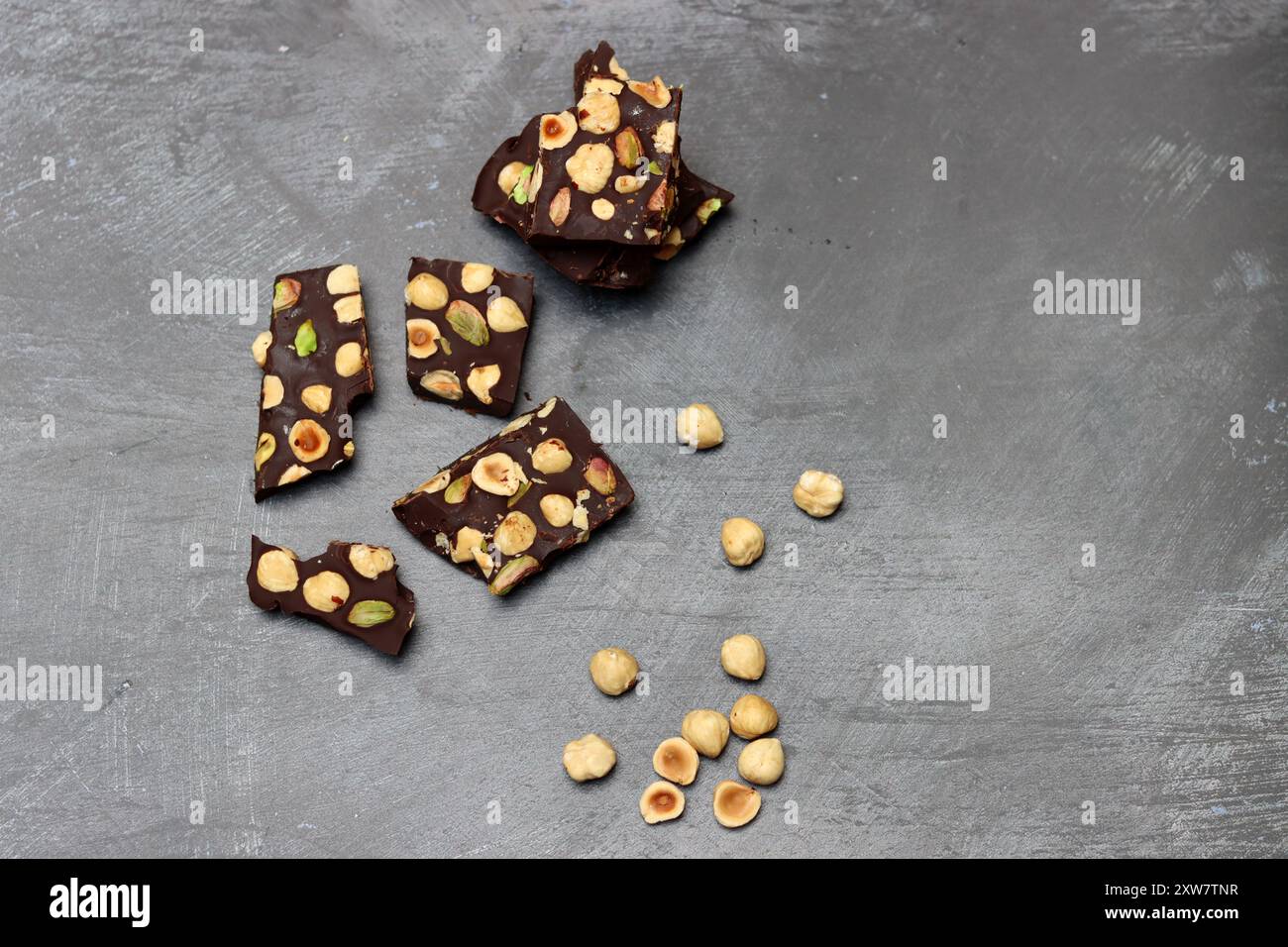 Pieces of dark chocolate with nuts on a gray background, top view, copy ...