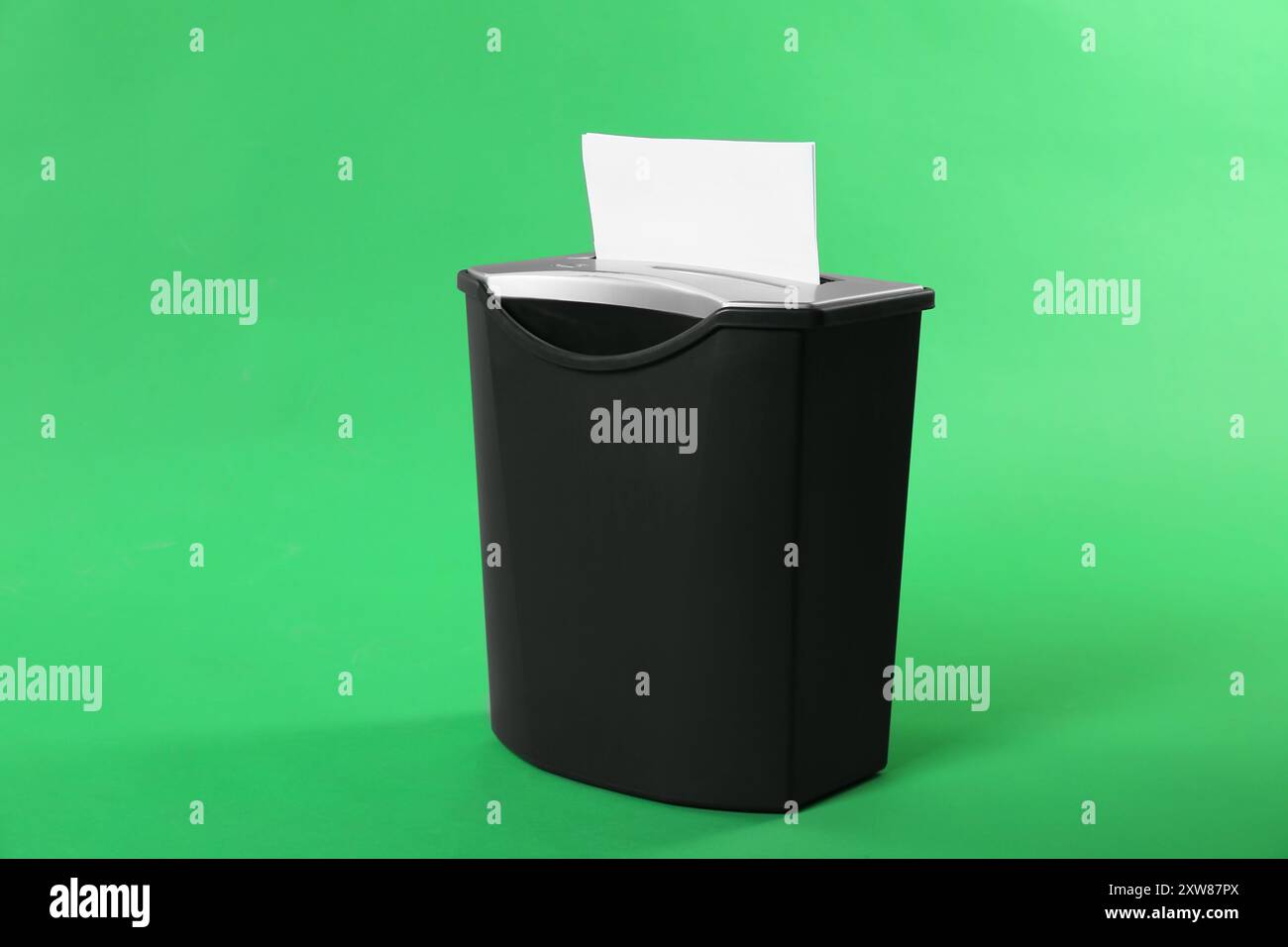 Shredder with sheet of paper on green background Stock Photo - Alamy