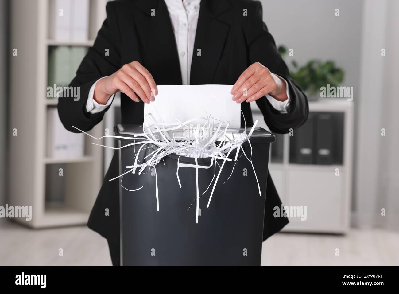Woman destroying sheet of paper with shredder in office, closeup Stock ...