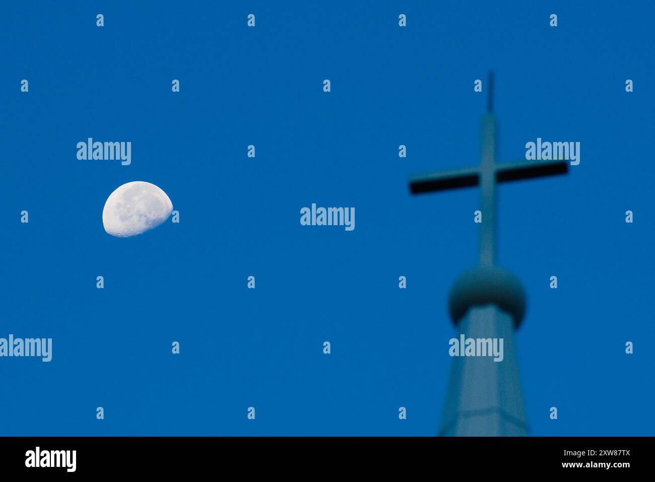 The moon in the early morning next to a cross on top of a church ...