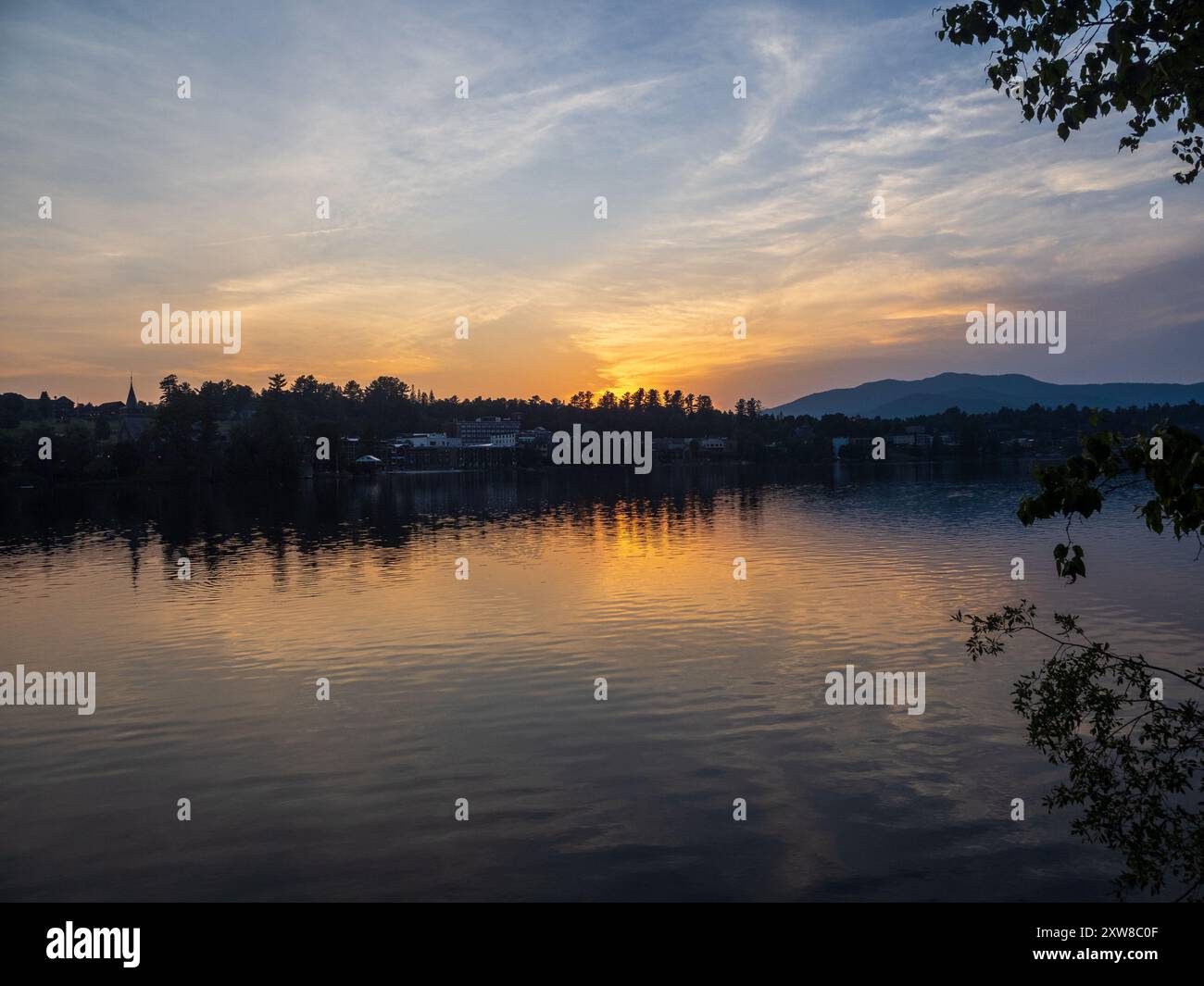 A breathtaking sunset casts golden hues over Lake Placid, reflecting ...