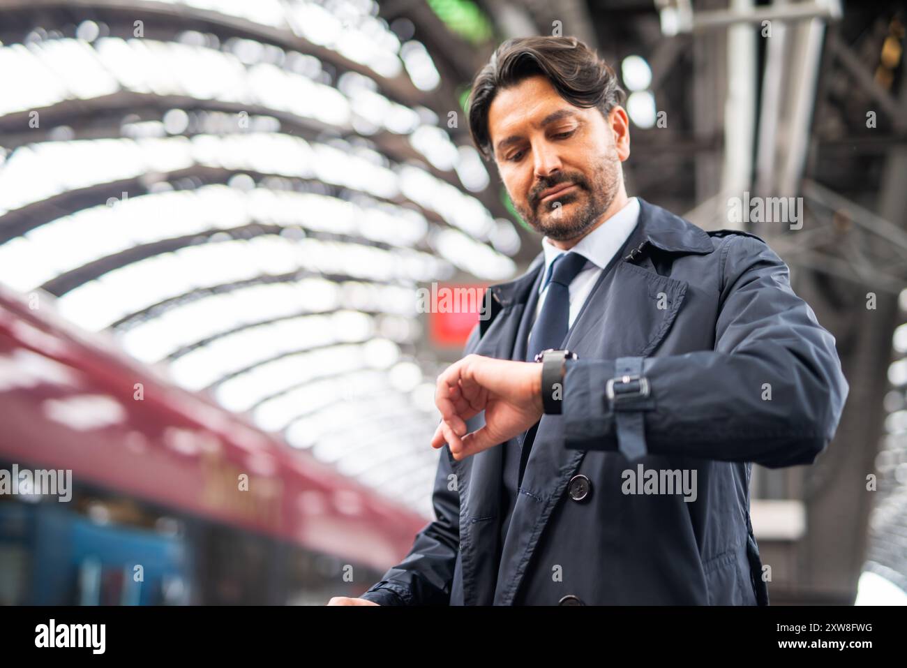 Man watching his watch while waiting for the train to arrive in a ...