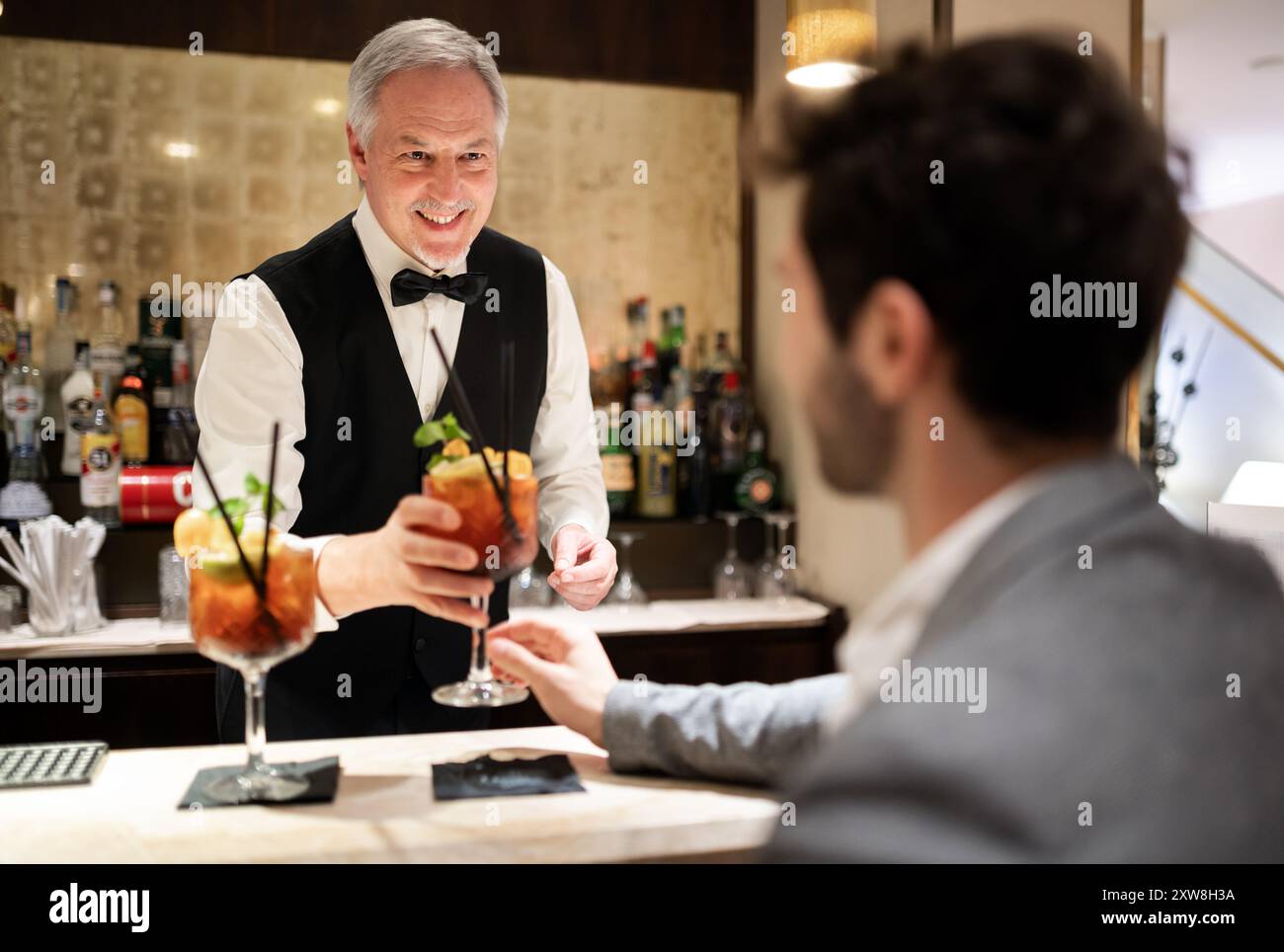 Mature waiter serving cocktails to a man in a luxury hotel Stock Photo ...