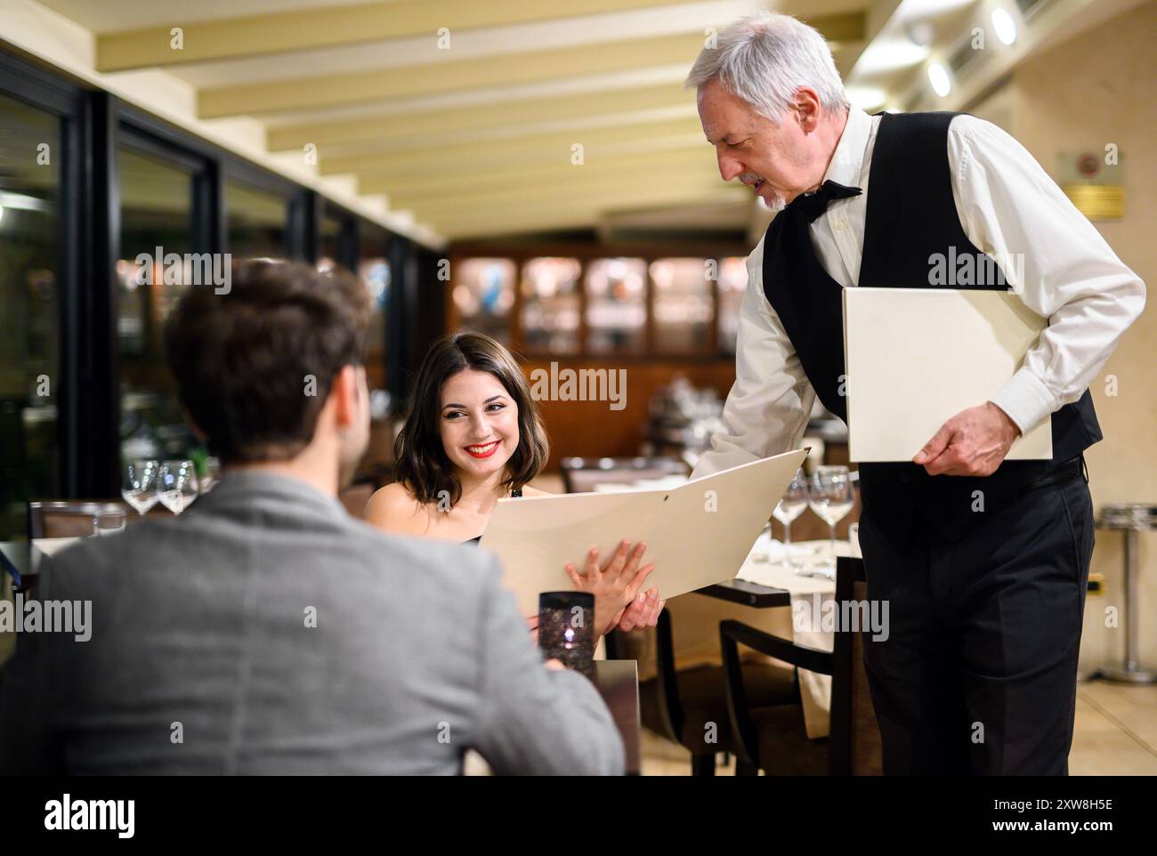 Waiter giving a menu to a couple in an elegant restaurant Stock Photo ...