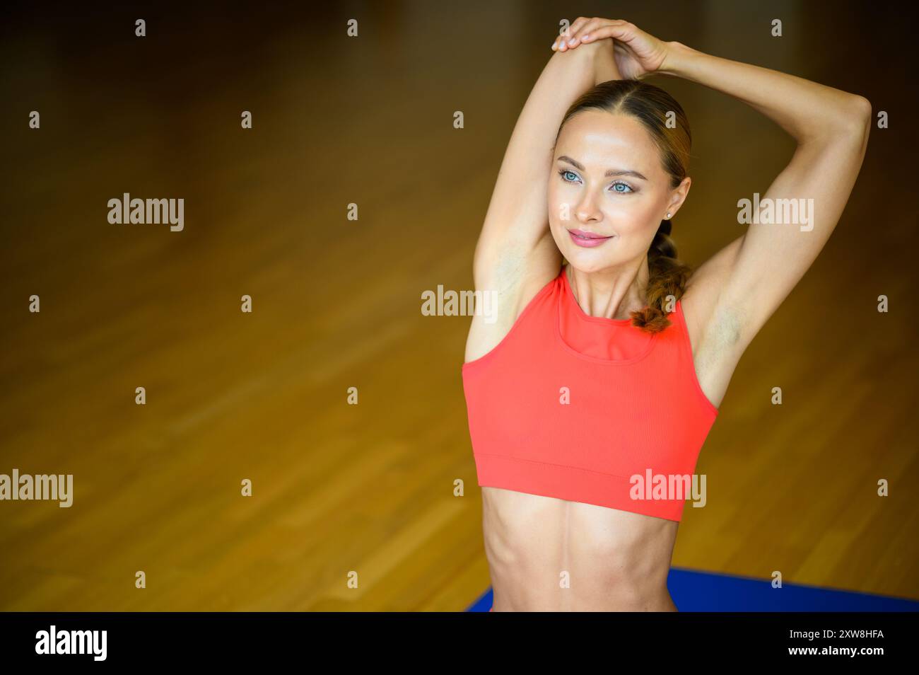 Toned woman with a braid stretches on a mat, exuding health and ...