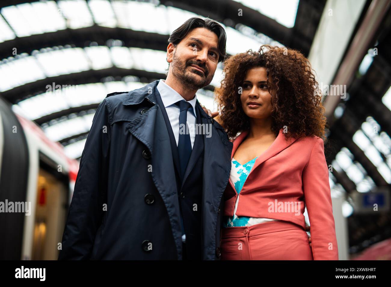 Confident man and woman waiting for a train, dressed in smart attire ...