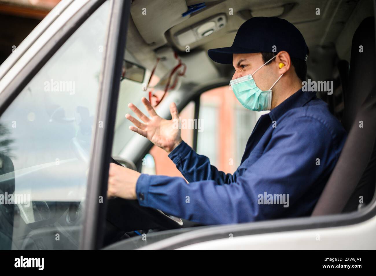 Male delivery driver in uniform with a mask for safety, yells nervous ...