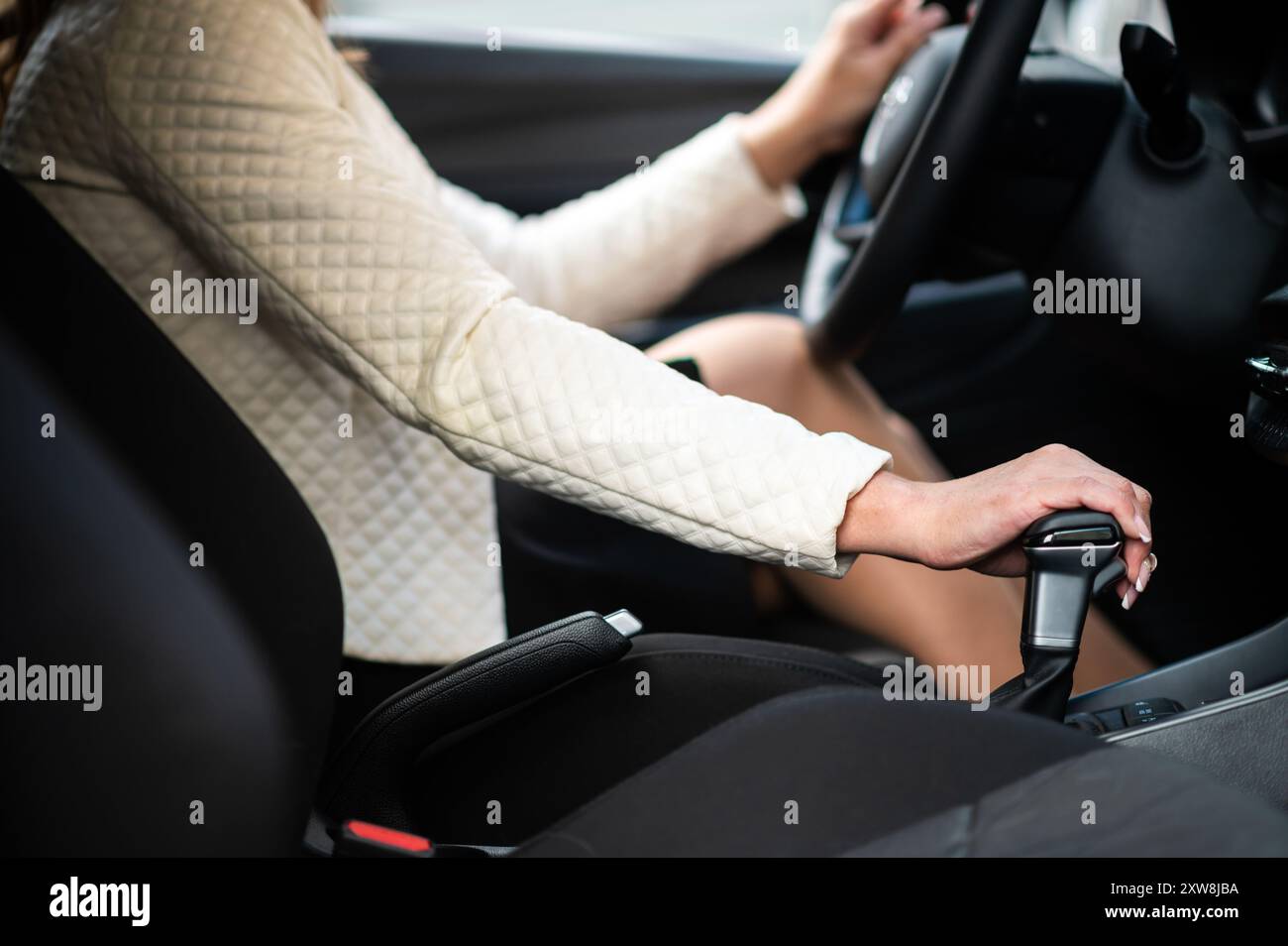 Close up of hand of female driver shifting gear stick before driving ...
