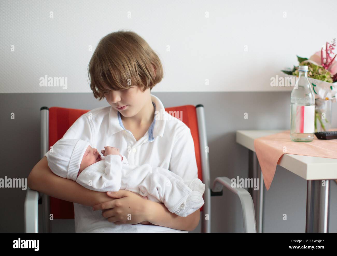 Siblings meet newborn baby in hospital. Child holding new infant ...