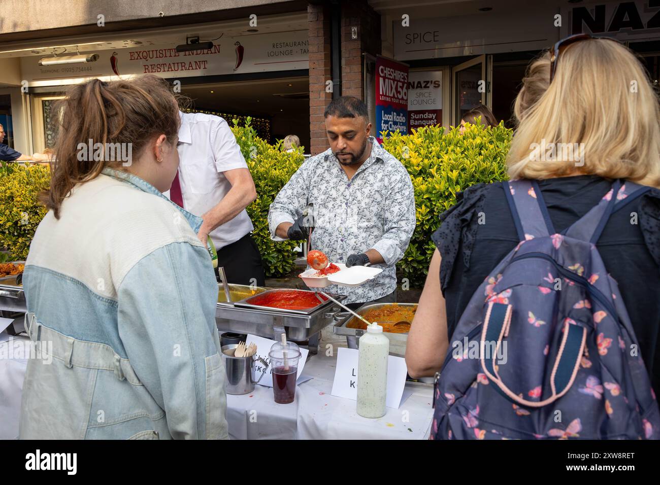 Indian man serving curry in the street at the Lymm Food Festival 2024 ...
