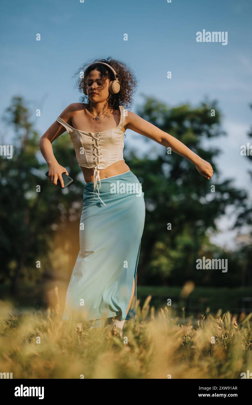 Young woman dancing freely in the sunny park with headphones Stock ...