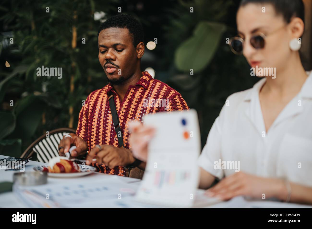 Diverse colleagues having lunch and working together at an outdoor cafe ...
