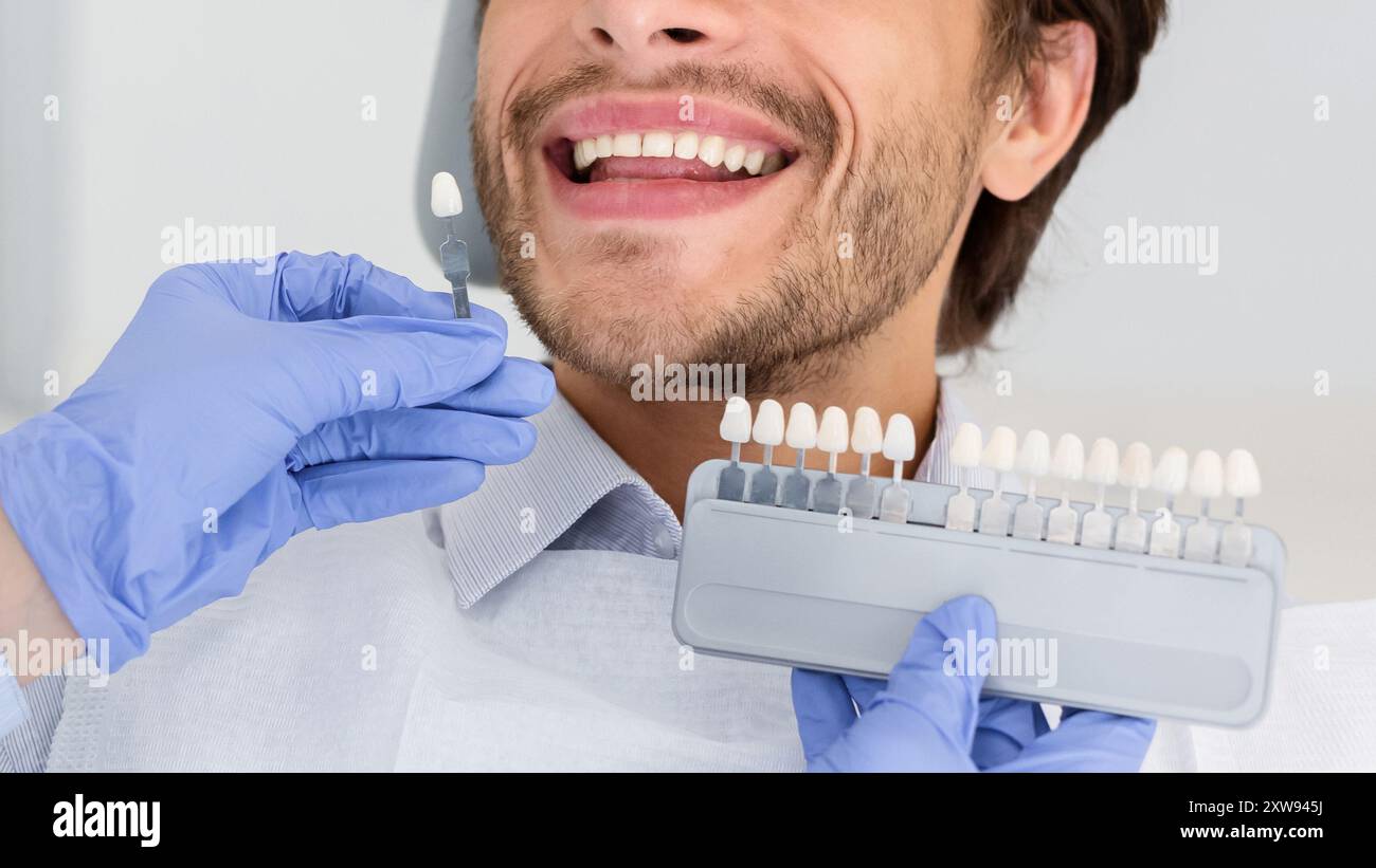 Dentist applying sample from tooth scale to smiling man teeth Stock ...