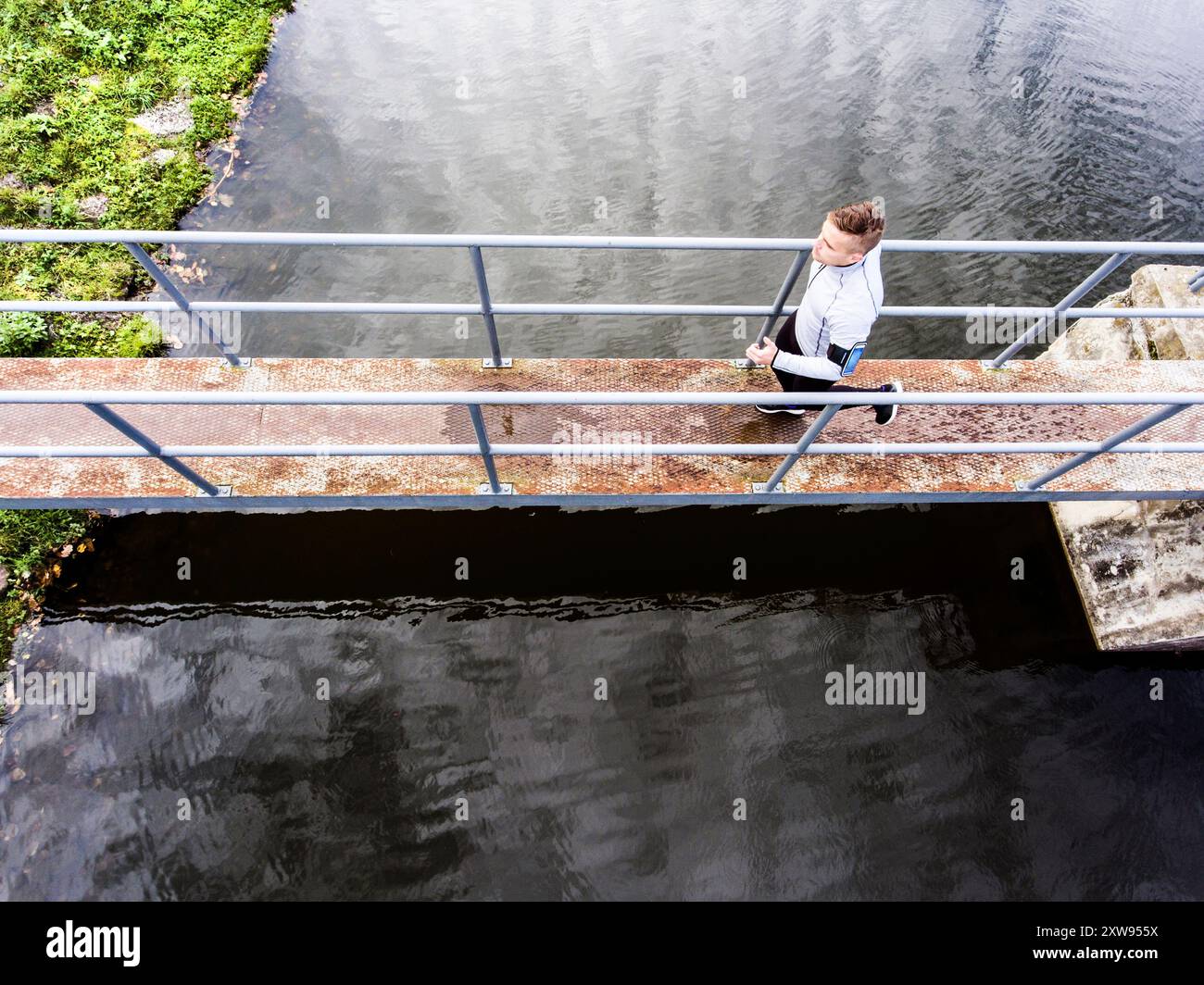 Aerial view of a runner running across bridge in park on a jogging path ...