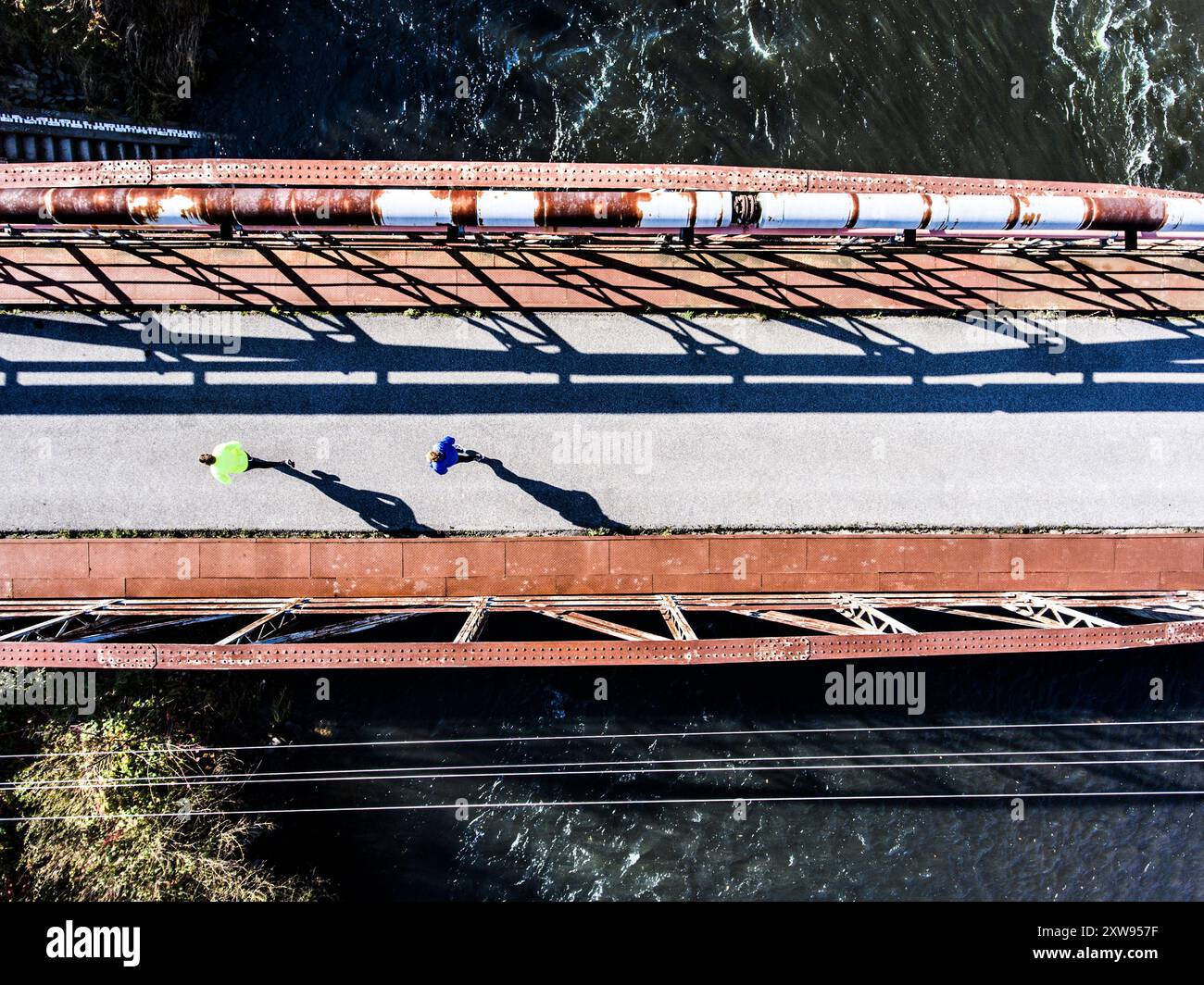 Aerial view of a runner running across bridge over the river. Morning ...