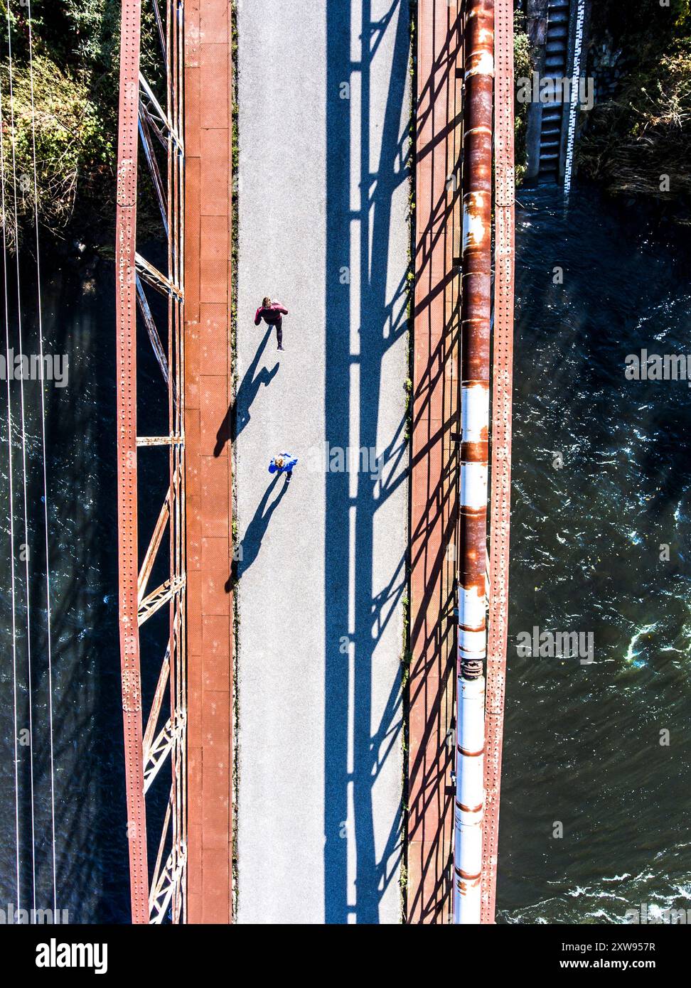 Aerial view of a runner running across bridge over the river. Morning ...