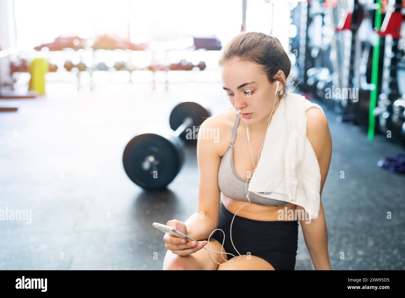 Young fitness girl checking her performance on smatphone after hard ...