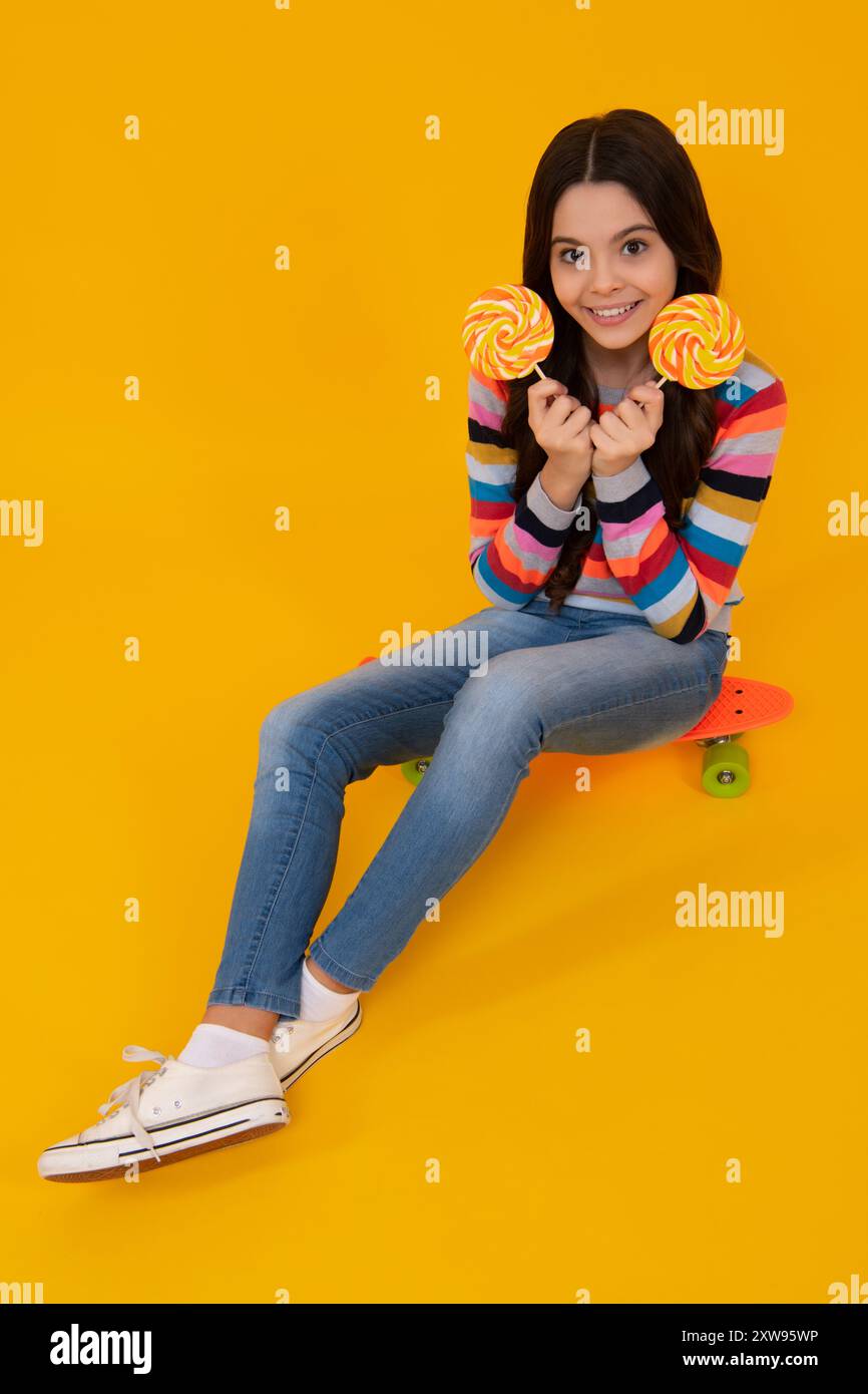 Cool teen child with lollipop over yellow isolated background. Sweet ...