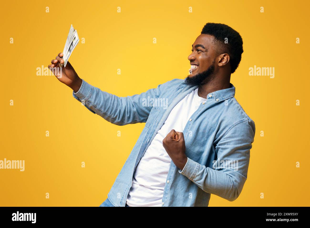 Happy black guy holding dollar cash celebrating success Stock Photo - Alamy