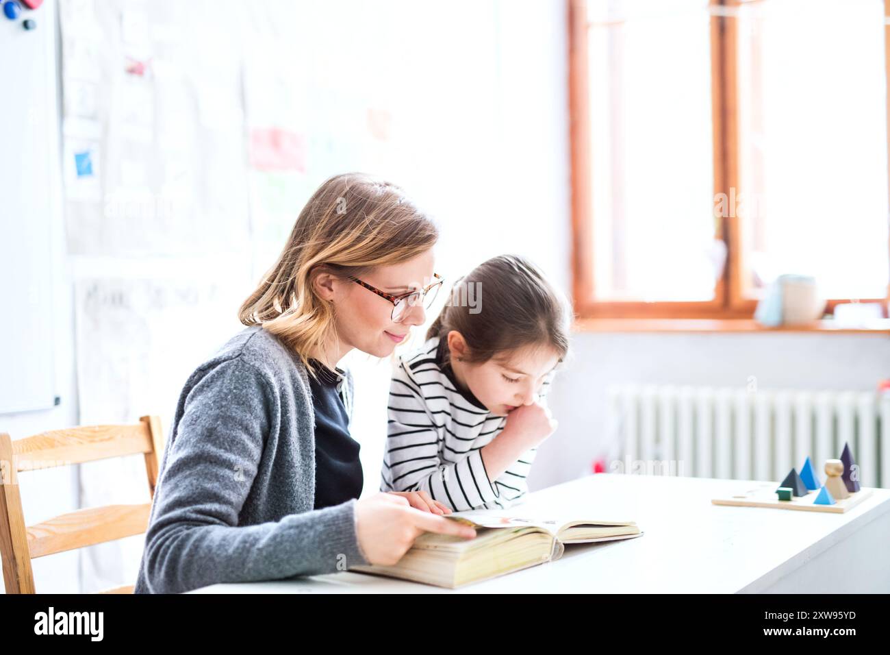 Hardworking teacher learning with young schoolgirl in classroom ...