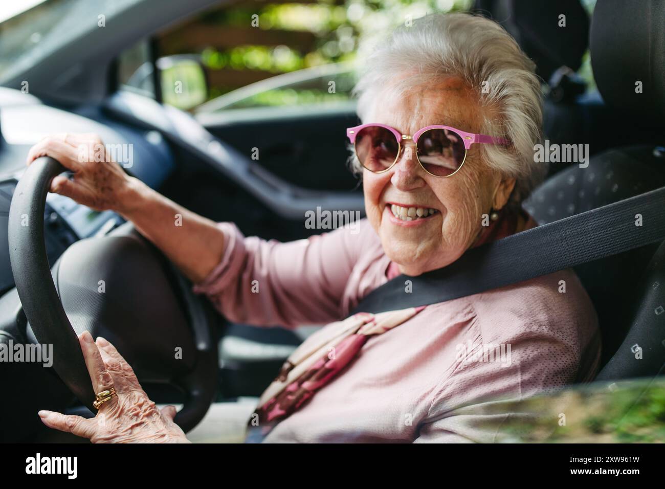Cool senior woman in sunglasses driving car alone, enjoying car ride ...