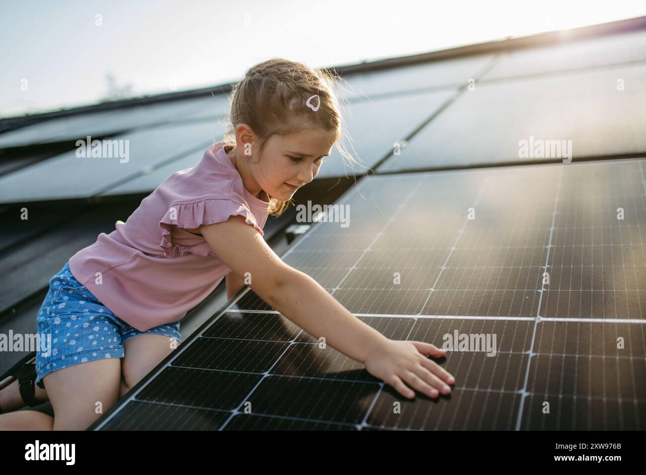 Cute girl sitting on solar panels roof, touching panel with hand ...