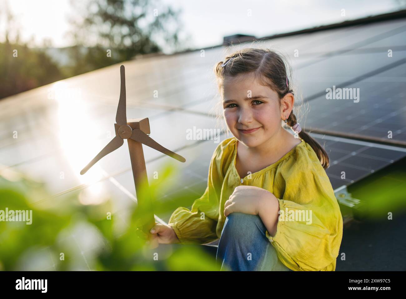 Cute girl on roof with solar panels, holding model of wind turbine ...