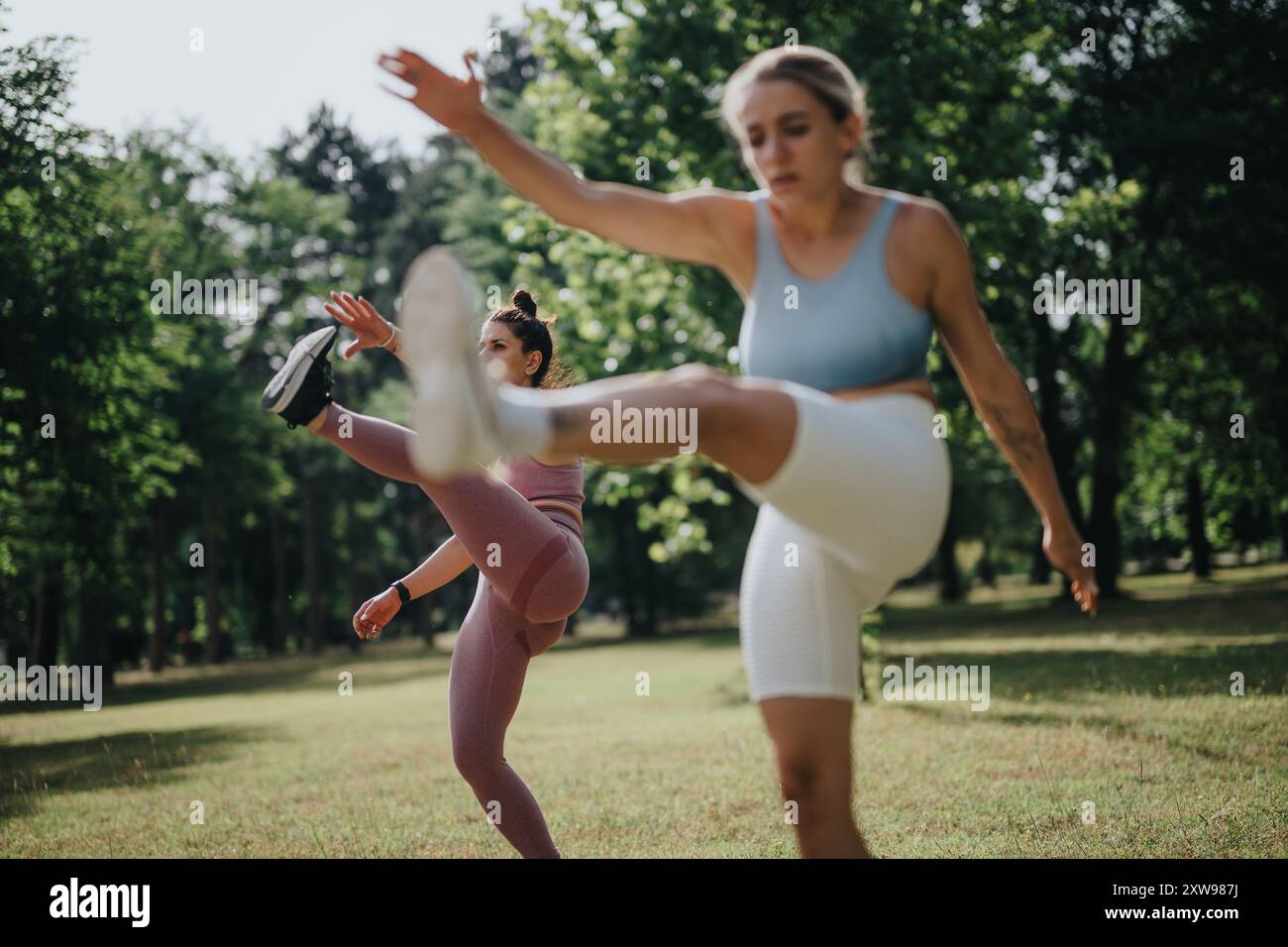 Two women performing calisthenics in a park setting for an outdoor ...