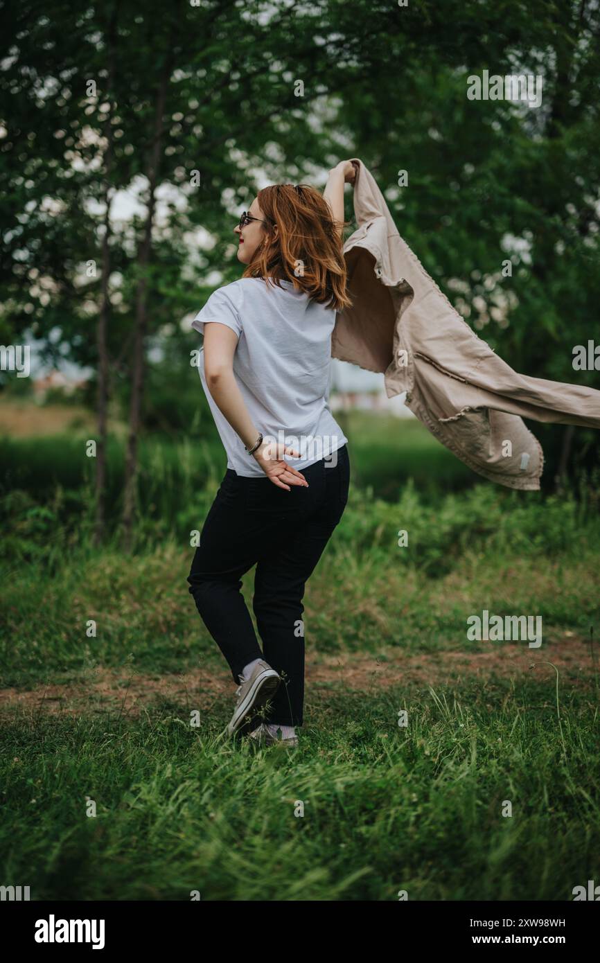 Woman joyfully walking in nature with jacket over her shoulder Stock ...