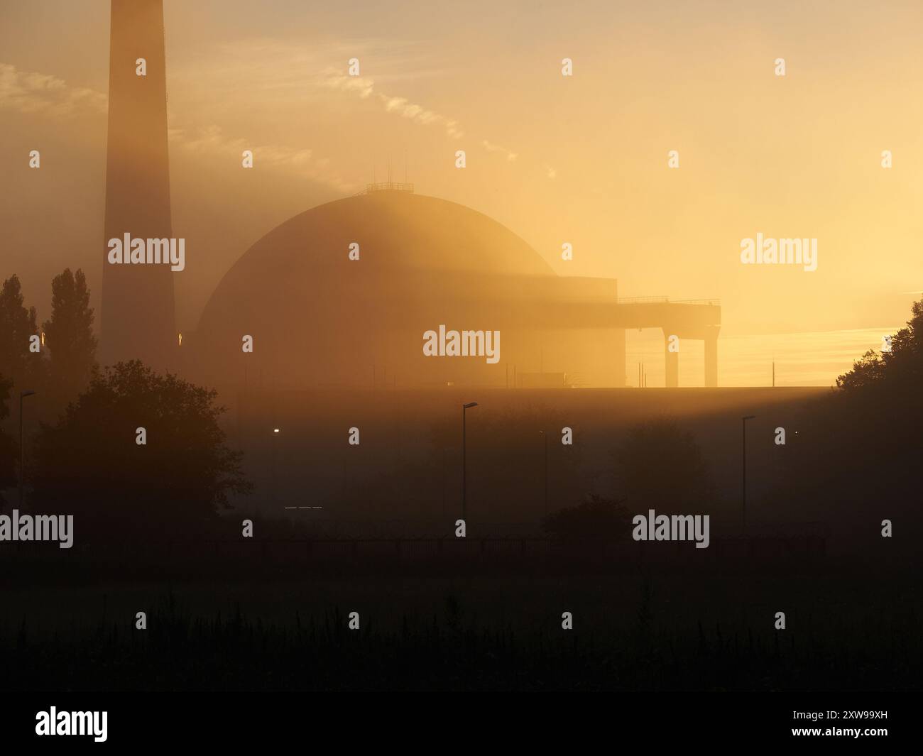 Pipe and nuclear reactor dome in dusty sunset rays with trees in ...