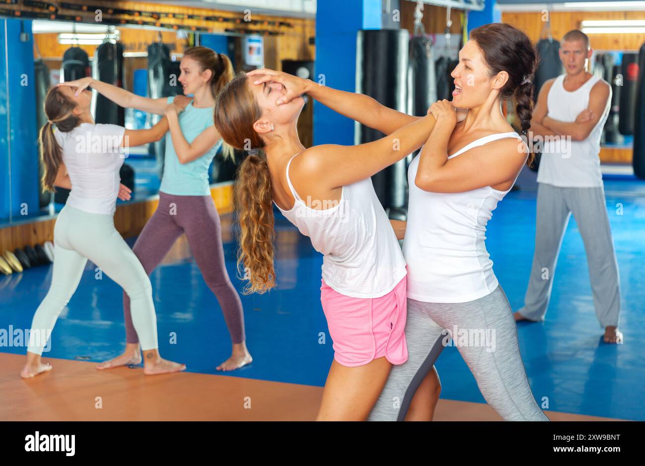 Asian woman blocking hand of female opponent and launching palm blow in ...