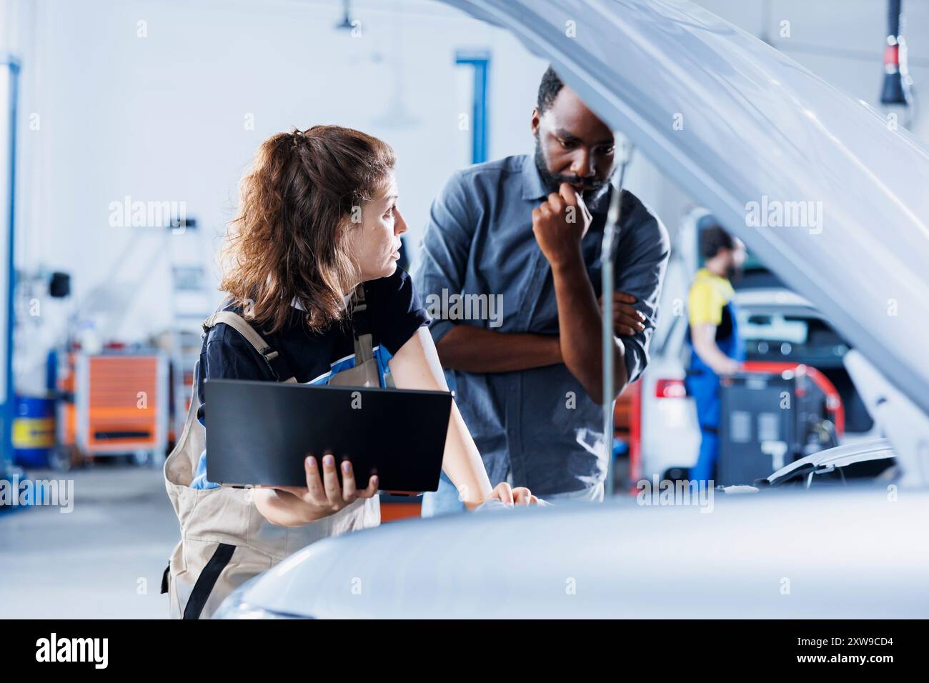 Mechanic in car service uses laptop to calculate invoice after fixing ...