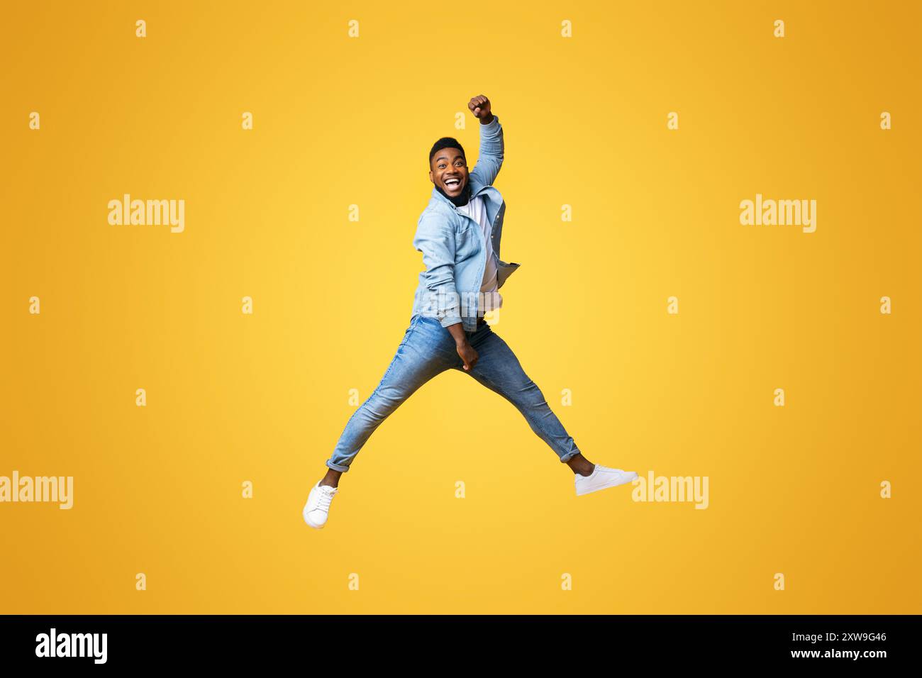 Full length of funny afro guy jumping against yellow studio background ...