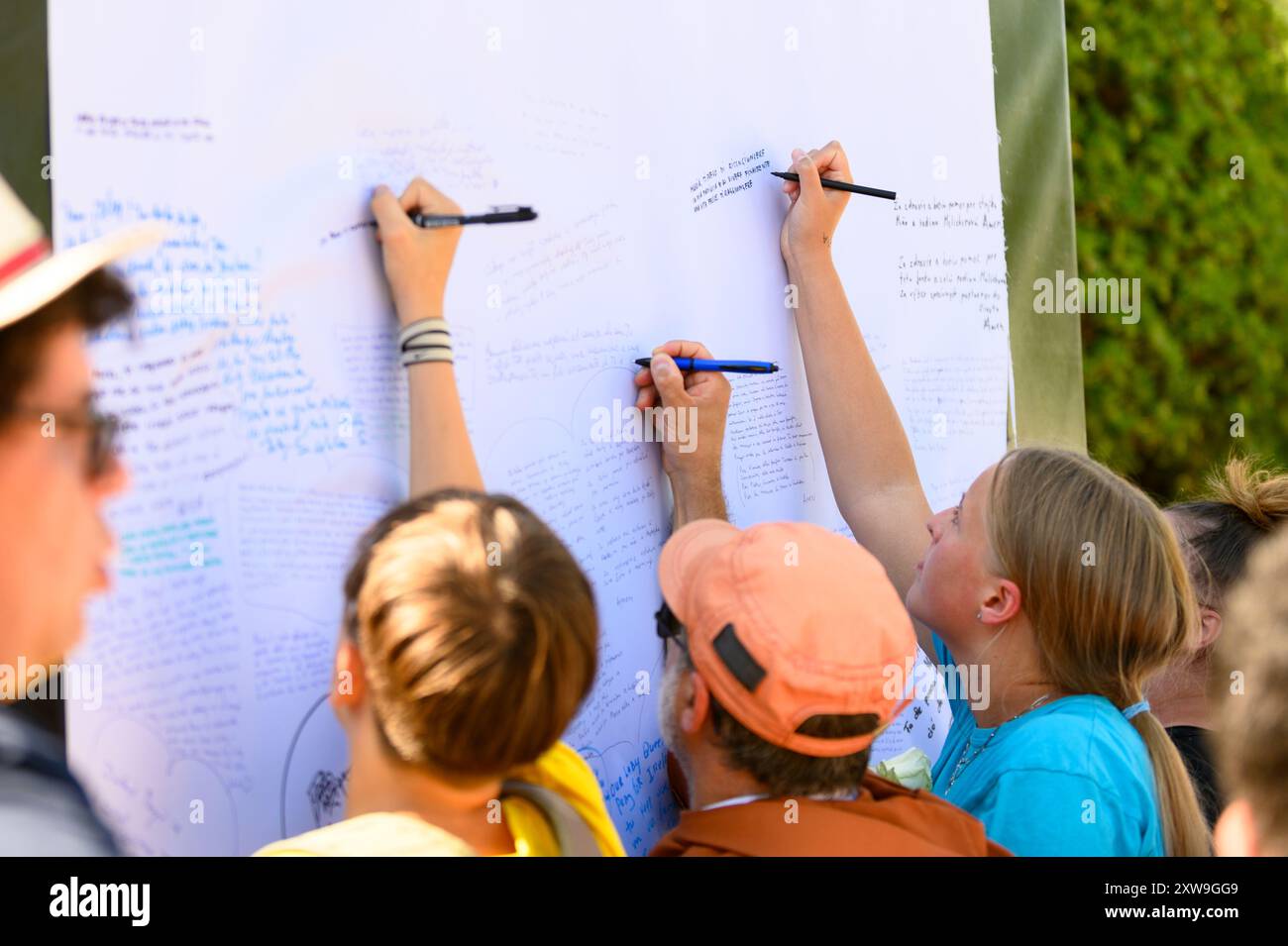 Young people writing their prayers onto a long roll of canvas at ...