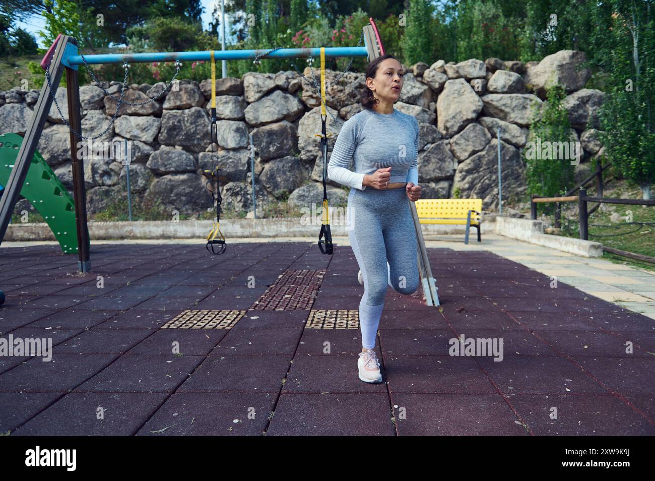 Woman in a grey outfit performing fitness exercises at an outdoor ...
